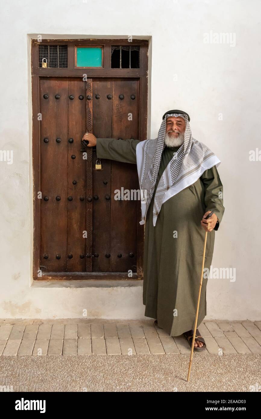 Man in thobe, keffiyeh and igal by an old doorway, Souk Al Arsah ...
