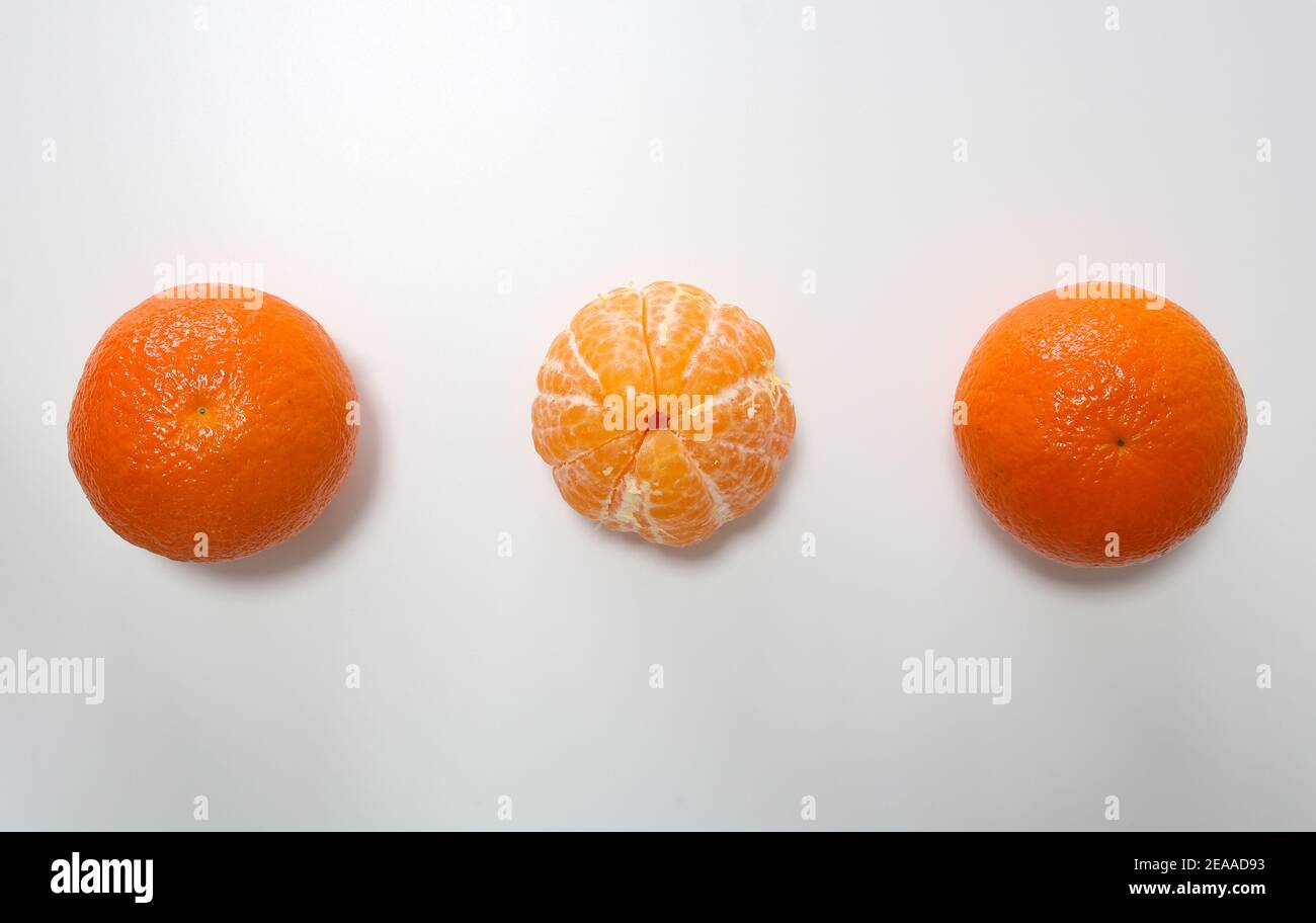 Three tangerines with middle one peeled off on white background with ...