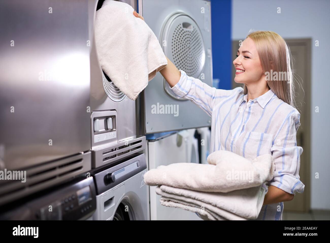 woman loading linen towels into washing machine, young caucasianfemale ...