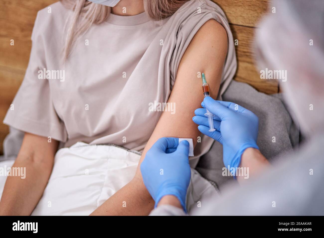 cropped doctor with syringe doing injection vaccine to young female ...