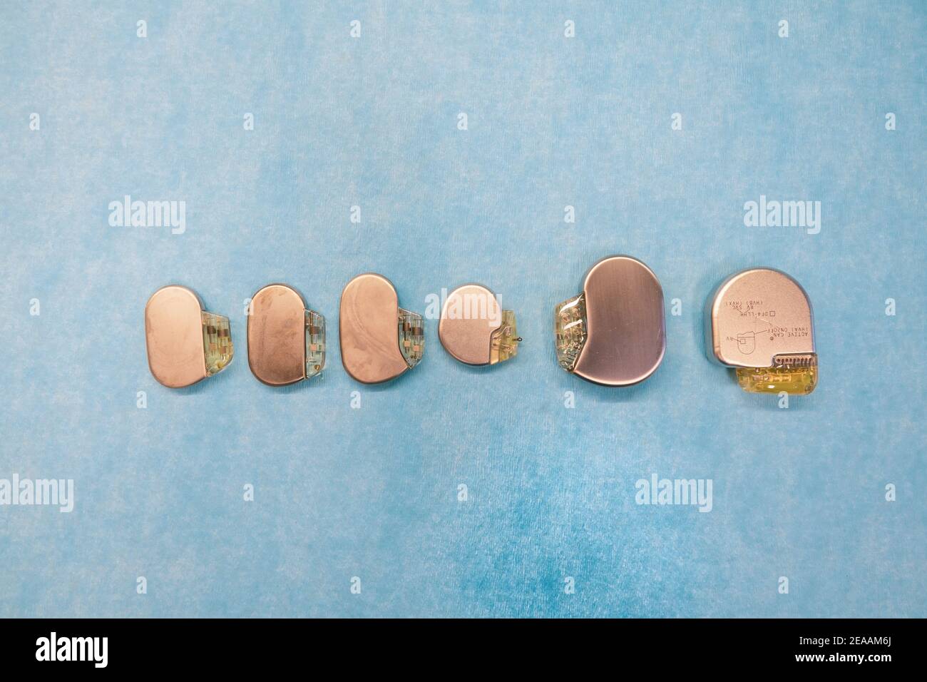 various pacemakers and implantable defibrilators lie on a light blue ...