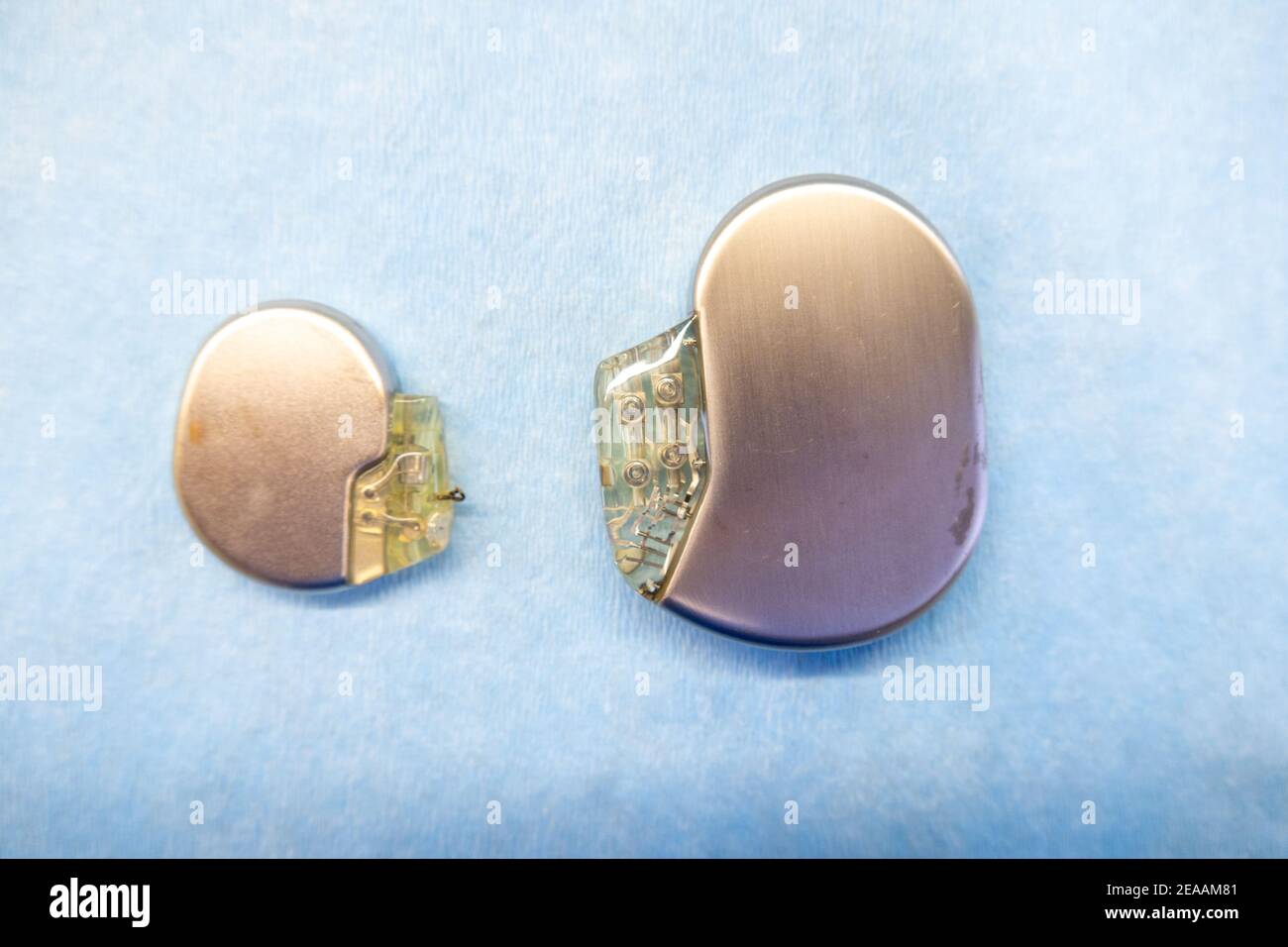 a pacemaker and an implantable defibrillator lying on a light blue base ...