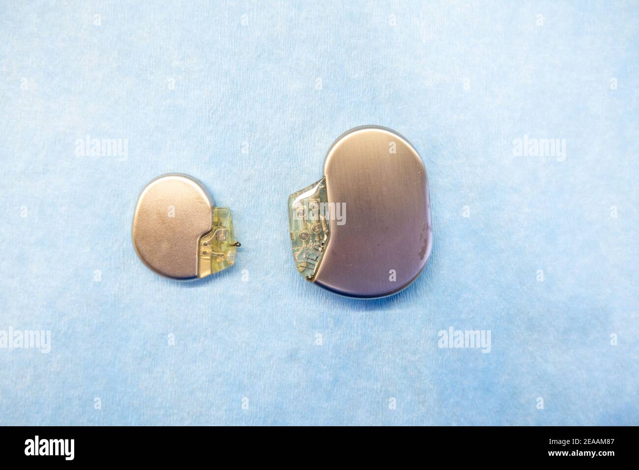 a pacemaker and an implantable defibrillator lying on a light blue base ...