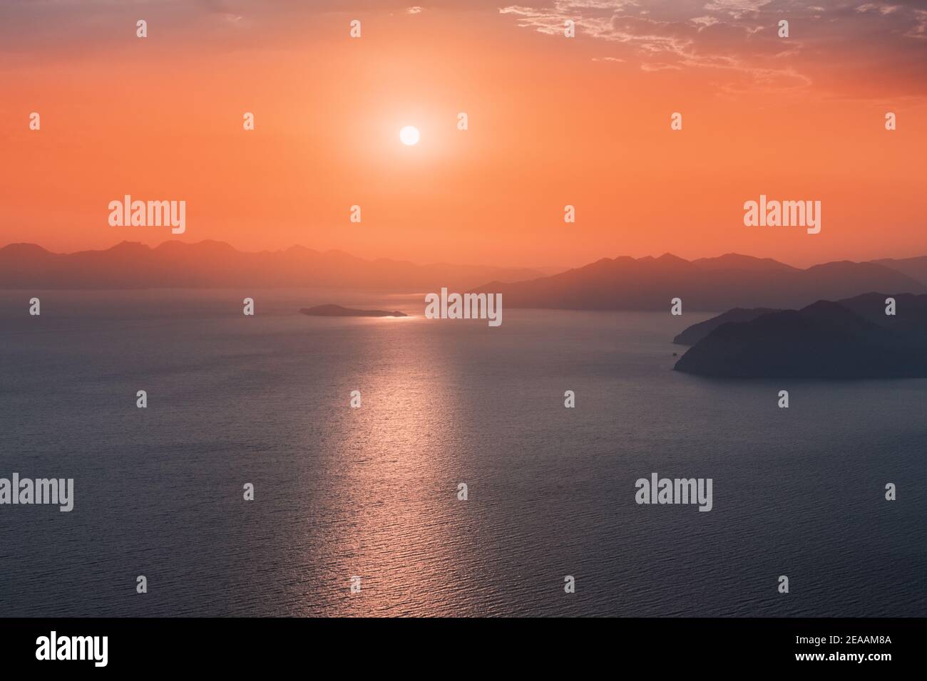 Moody sunset, the distant sun sets behind the silhouettes of blue ...