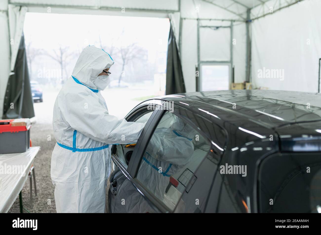 Nurse in a protective suit taking a sample from the driver inside the ...