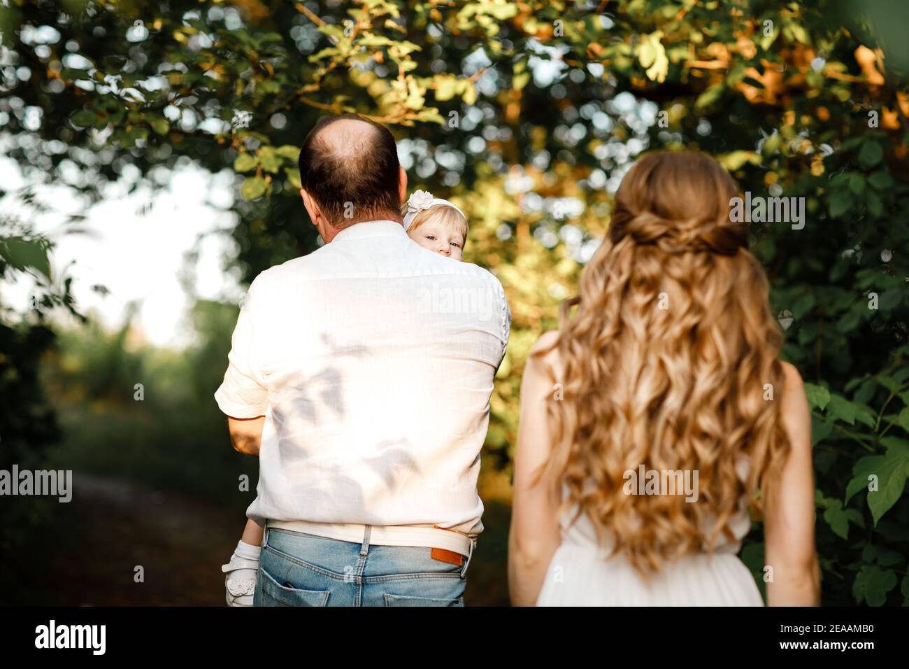 Young parents hugging each other and holding on the hands their little ...