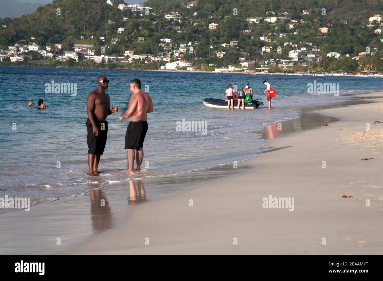 tourist and grenadian man talking and drinking at waters edge grand ...