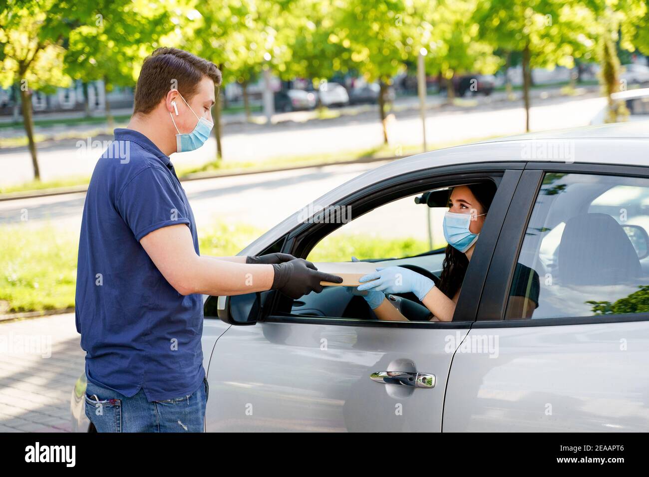 Food delivery courier gives pizza to woman in eco car. Safety food ...