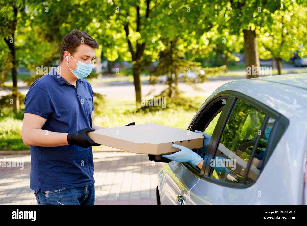 Food delivery courier gives pizza to woman in eco car. Safety food ...