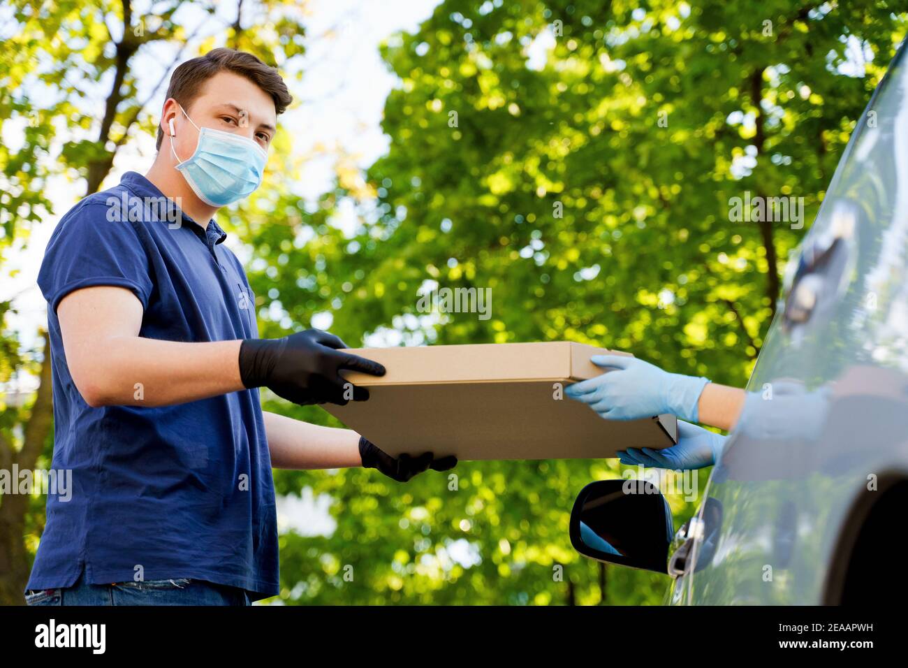 Food delivery courier gives pizza to woman in eco car. Safety food ...