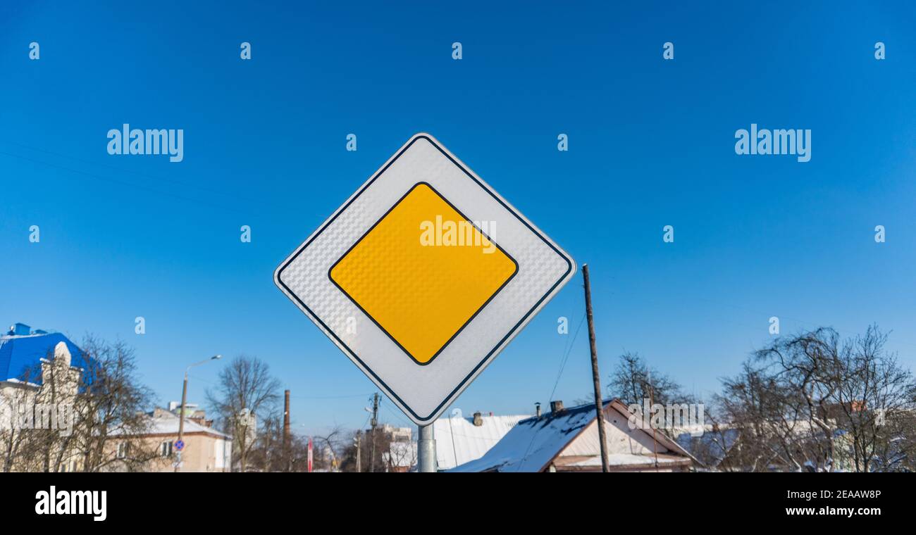 Sign main road, priority road sign on roofs of houses background Stock ...