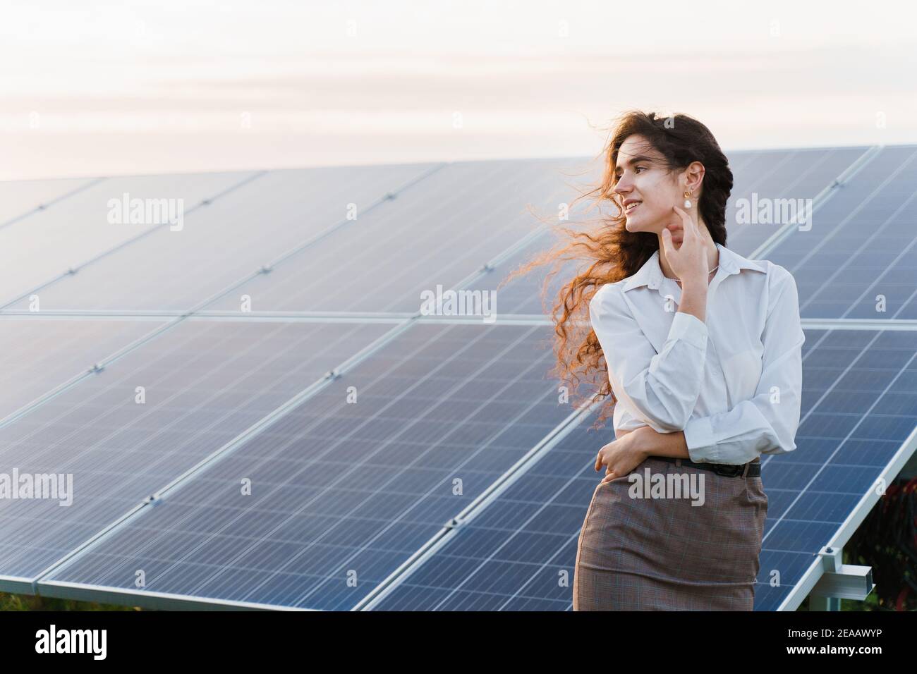 Model with solar panels stands in row on the ground at sunset. Girl ...