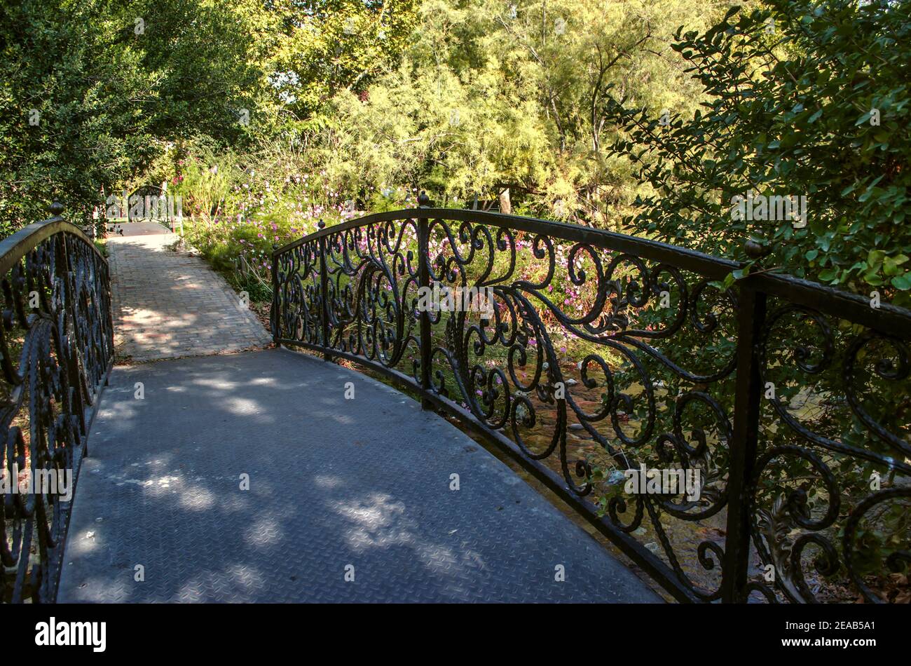 An iron bridge with wrought iron railings stands on an artificial ...