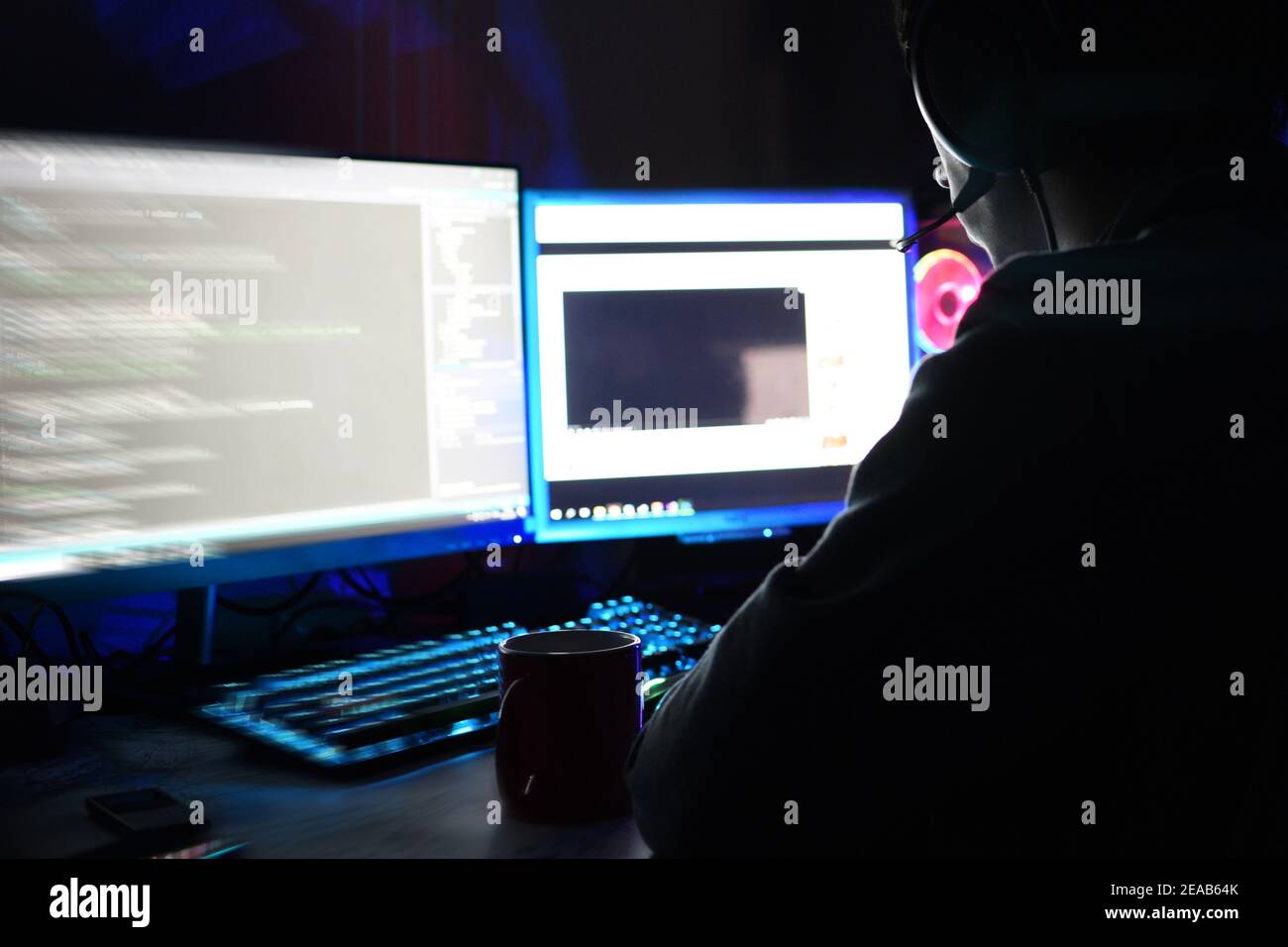 person with headphones using two computer monitors at home Stock Photo ...