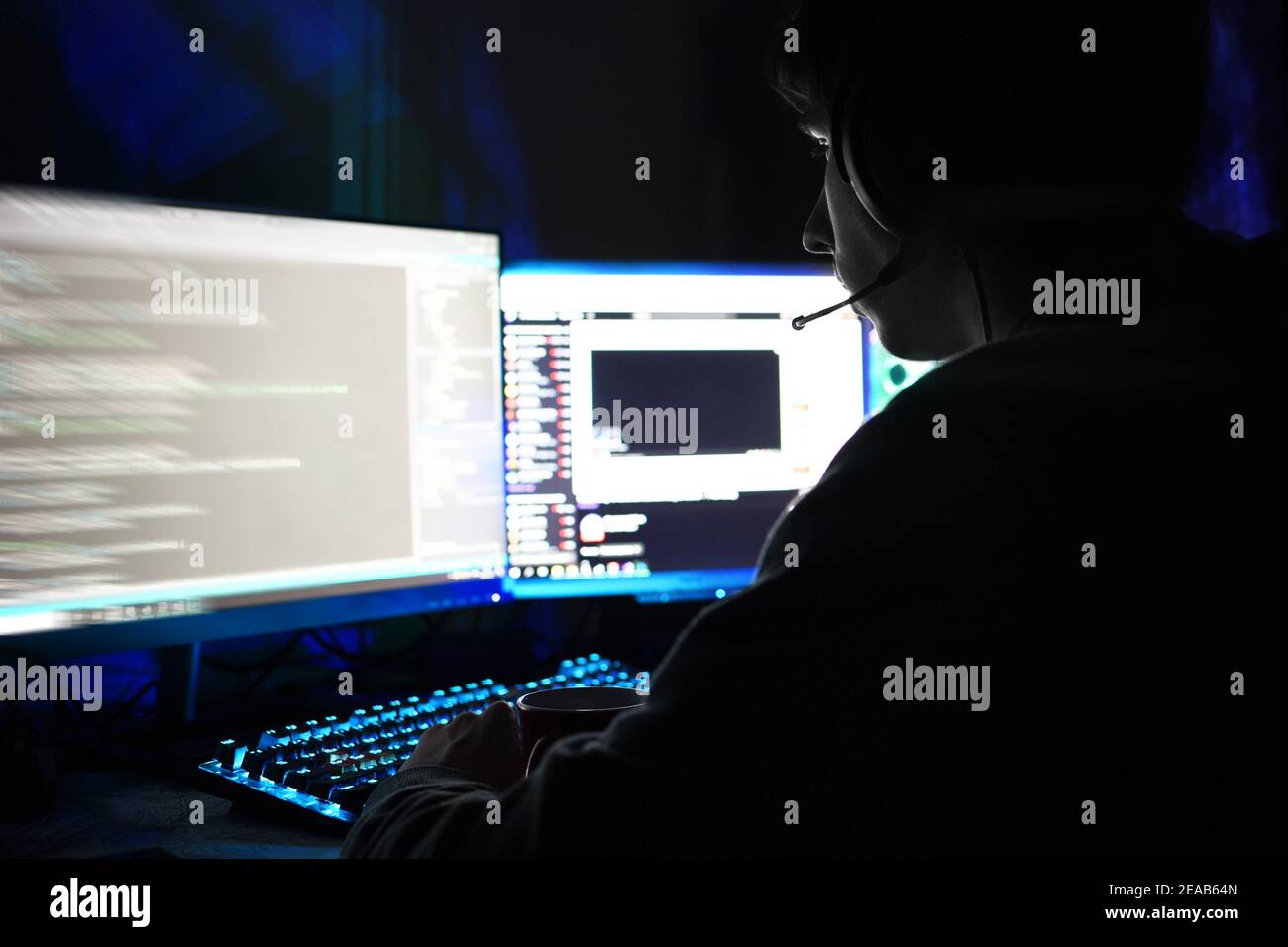 person with headphones using two computer monitors at home Stock Photo ...