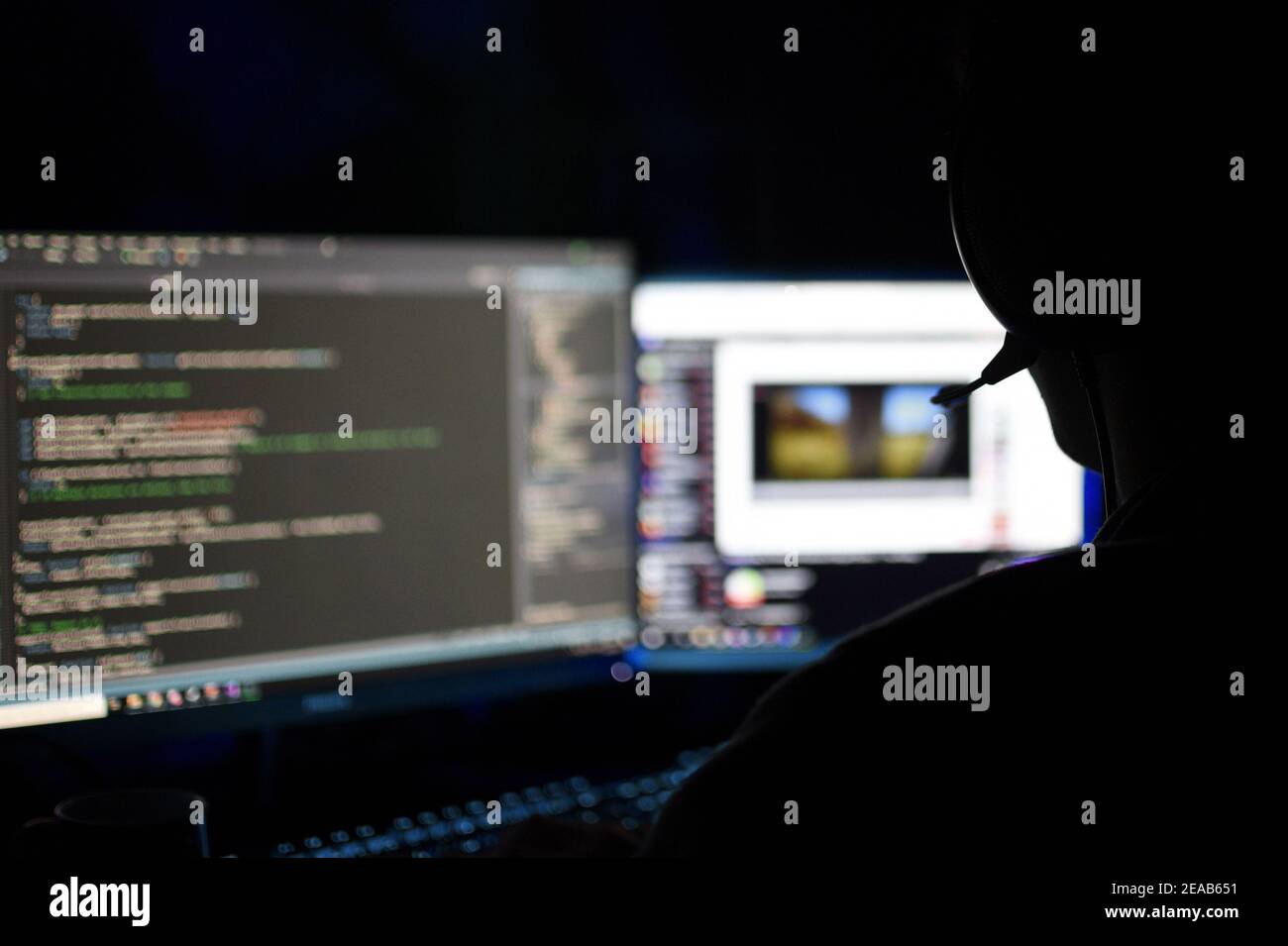 person with headphones using two computer monitors at home Stock Photo ...