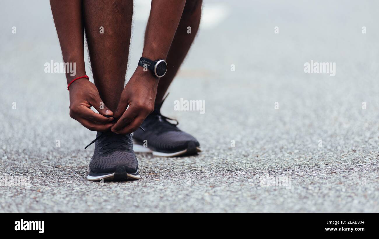 Close up Asian sport runner black man standing he trying shoelace ...