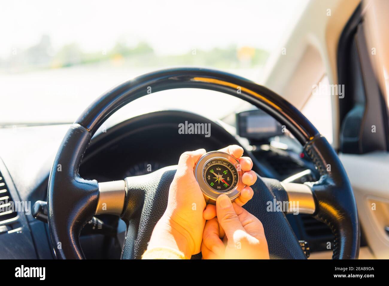 Asian woman inside a car and using compass to navigate while driving ...