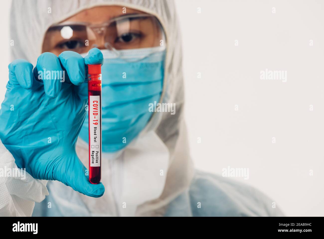 Medical scientist in PPE uniform wear a mask holding test tube ...