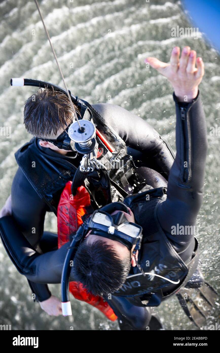 Navy search and rescue (SAR) student swimmers ascend up a rescue winch ...