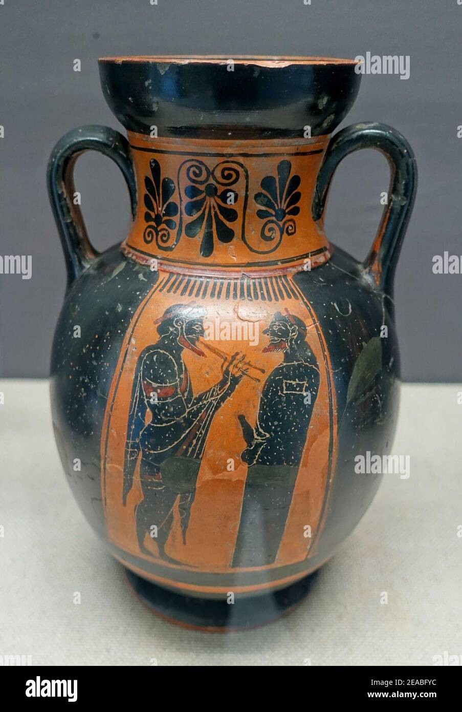 Neck amphora with cult scene of man playing a double aulos to a herm ...
