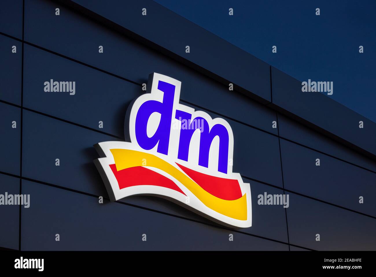 Illuminated dm logo on the building of a dm branch in Wilhelmshaven ...