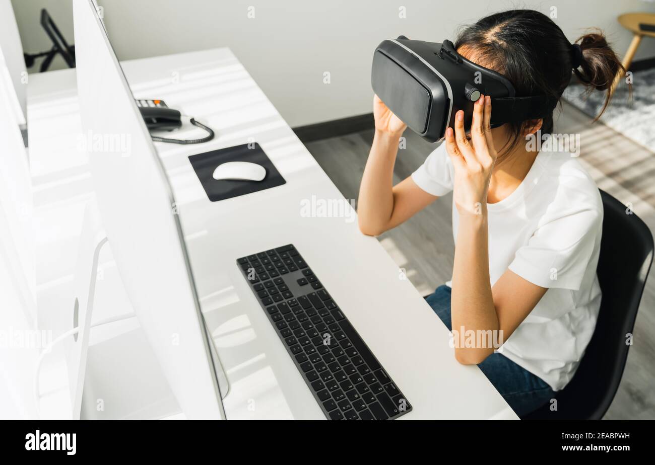 Excited young Asian woman using a virtual reality headset and joysticks ...