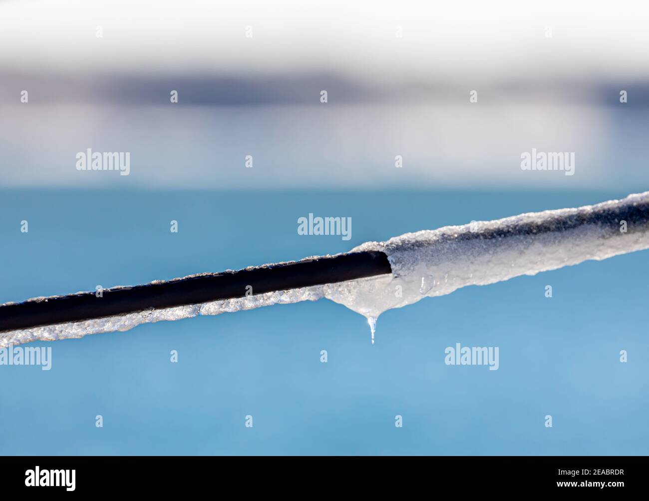 Black electrical line covered in ice Stock Photo - Alamy