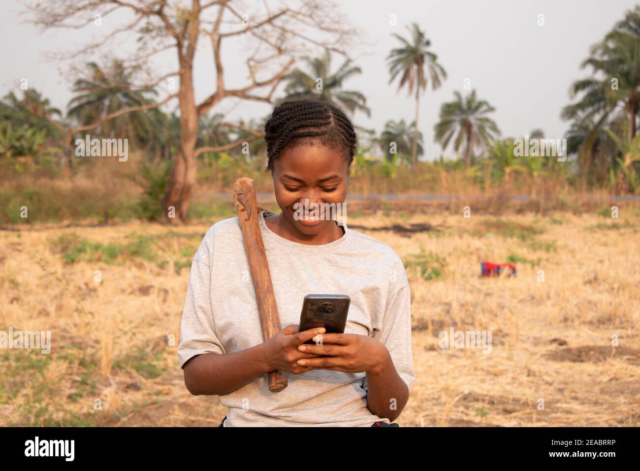 an african woman making a deal from her smartphone in the farmland ...