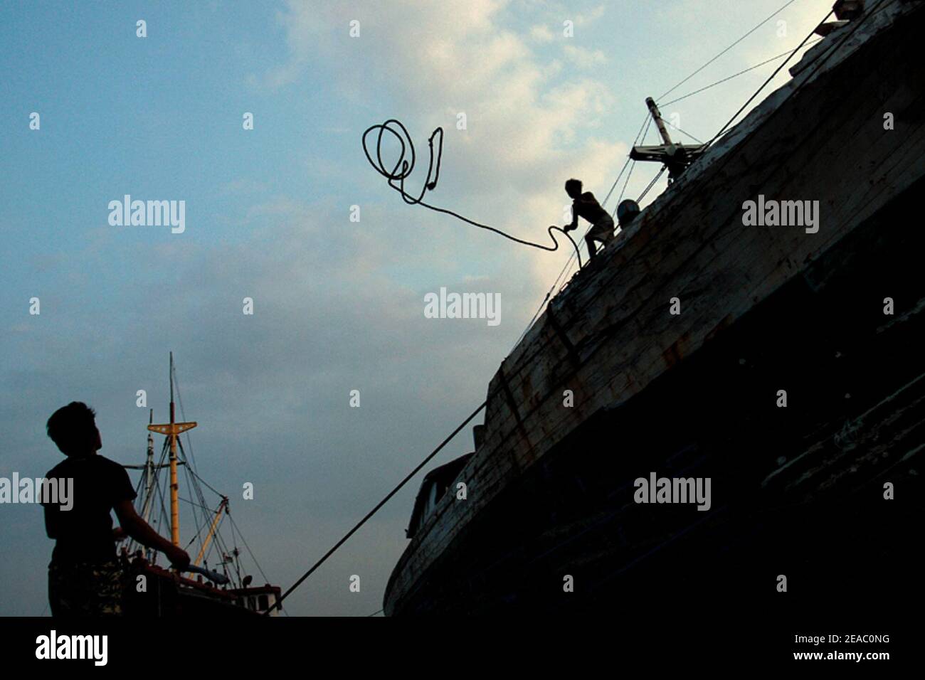 A boat crew throwing rope to port platform, where his colleague is ...