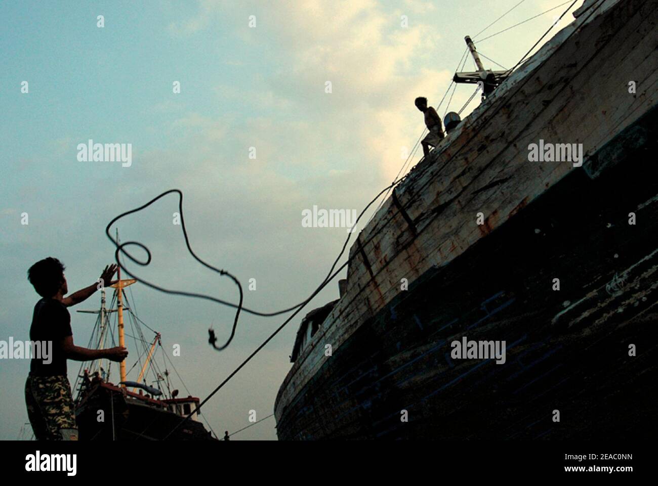 A boat crew throwing rope to port platform, where his colleague is ...
