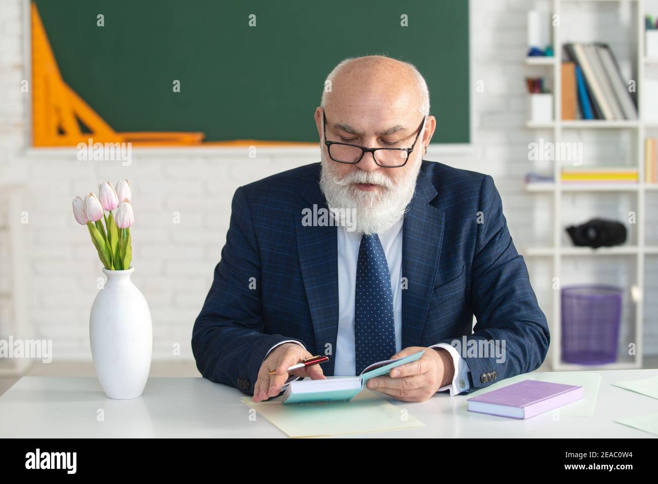 Old male teacher sitting in the classroom. Elderly Senior professor ...