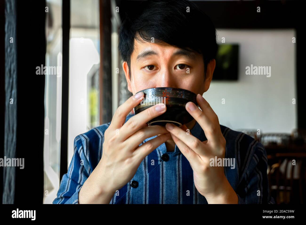 Young adult Chinese man in traditional costume drinking a cup of hot ...