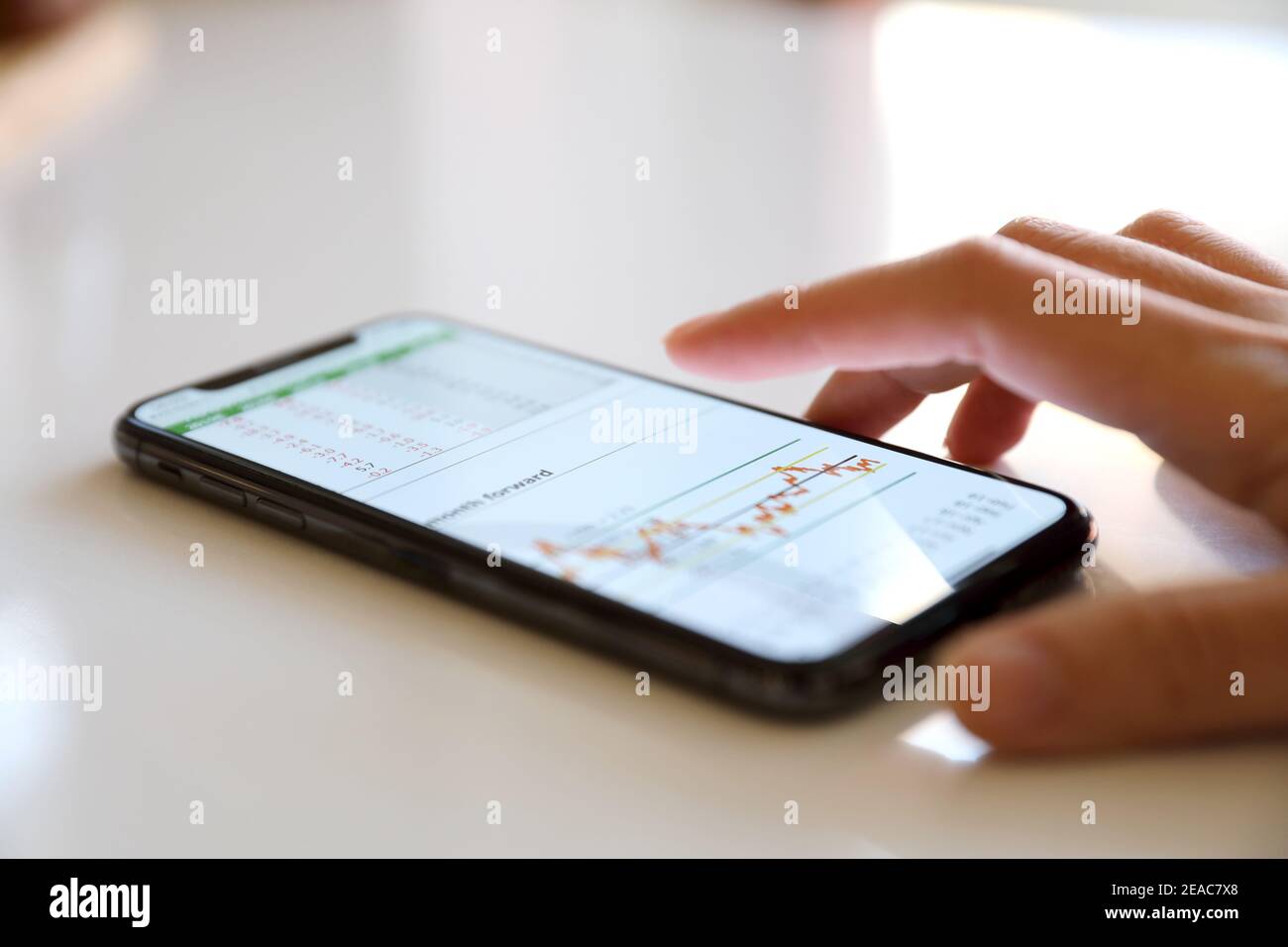 Female hand with smartphone trading stock online in coffee shop ...