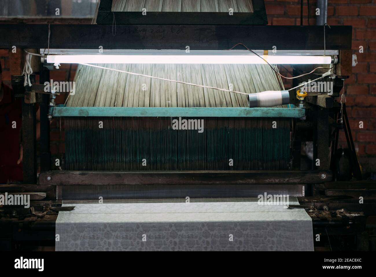 Close-up of old silk weaving machine running, creating silk cloth in ...