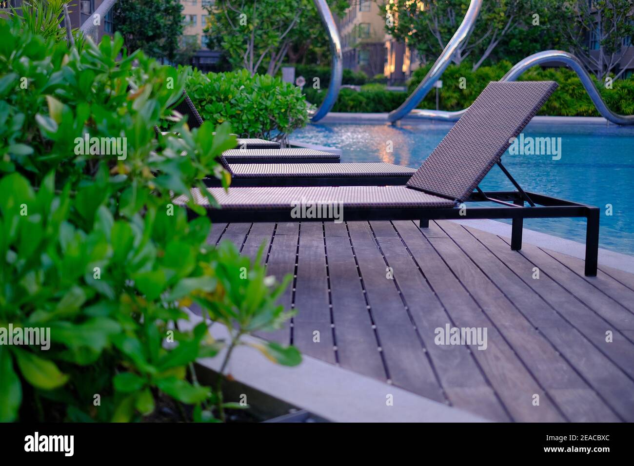 A poolside view with rows of wooden reclining chairs on the edge of a ...