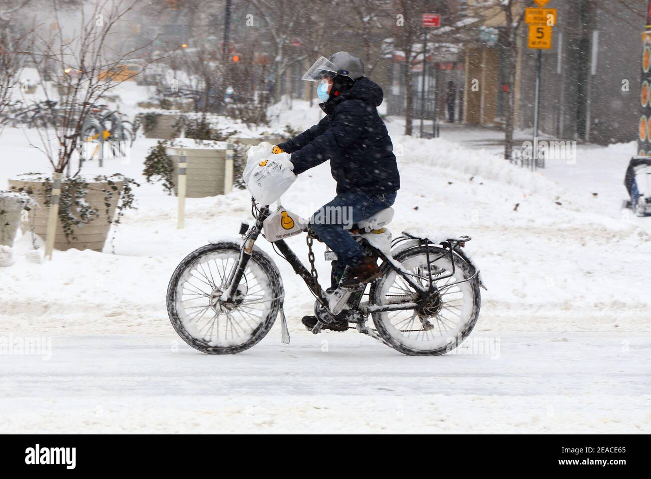 A food delivery person riding an ebike in snowy weather. New York, NY ...