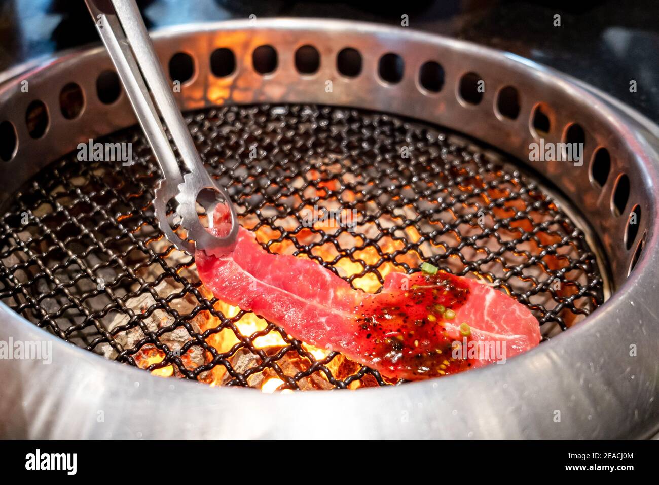 Close up raw beef slice on the grill ,over charcoal on stove,Japanese ...