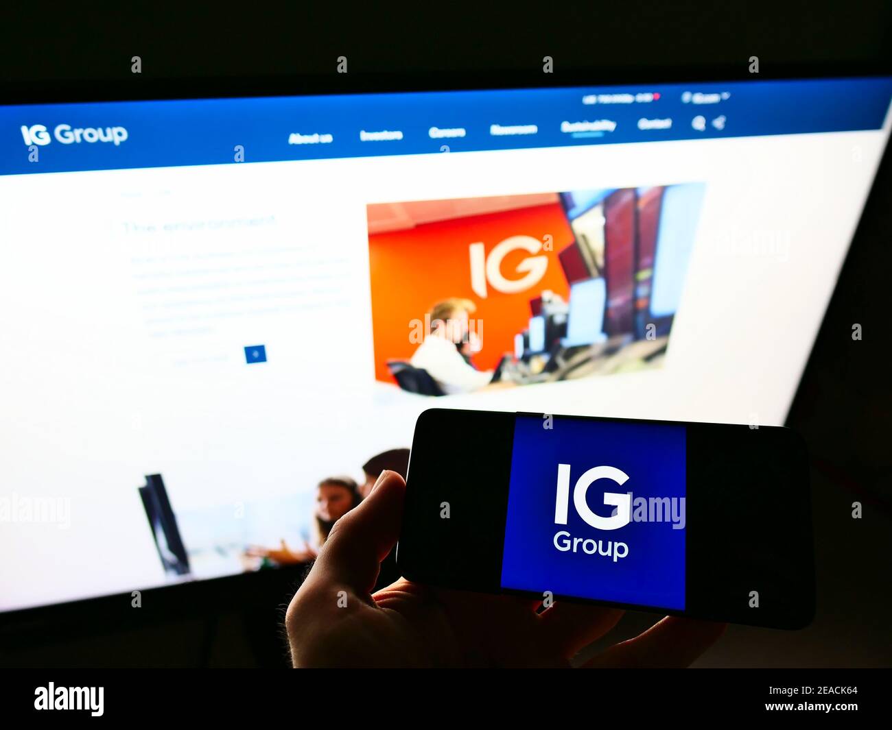 Person holding mobile phone with logo of British financial services company IG Group Holdings ...