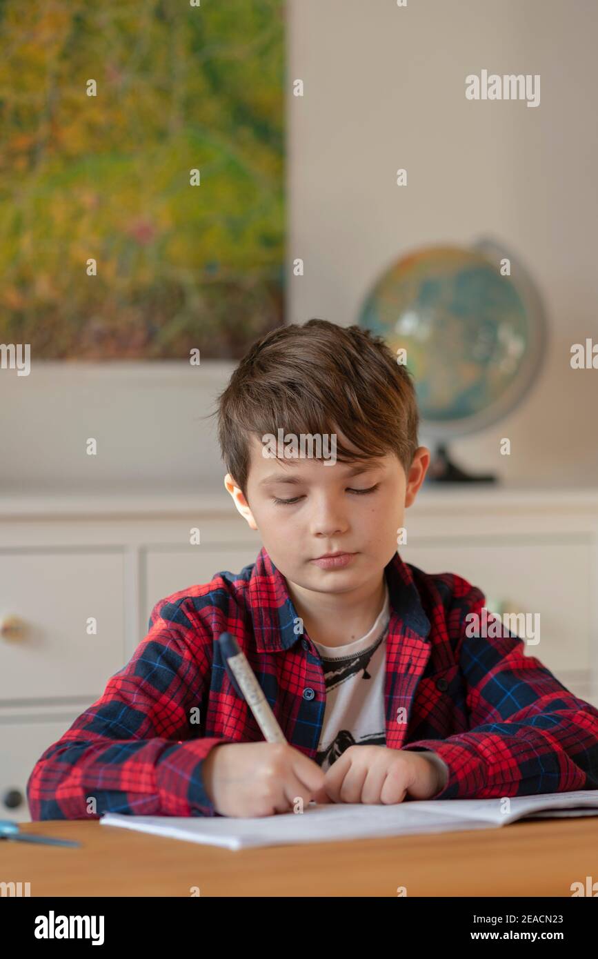 A boy sits at his desk in homeschooling doing chores for school Stock ...