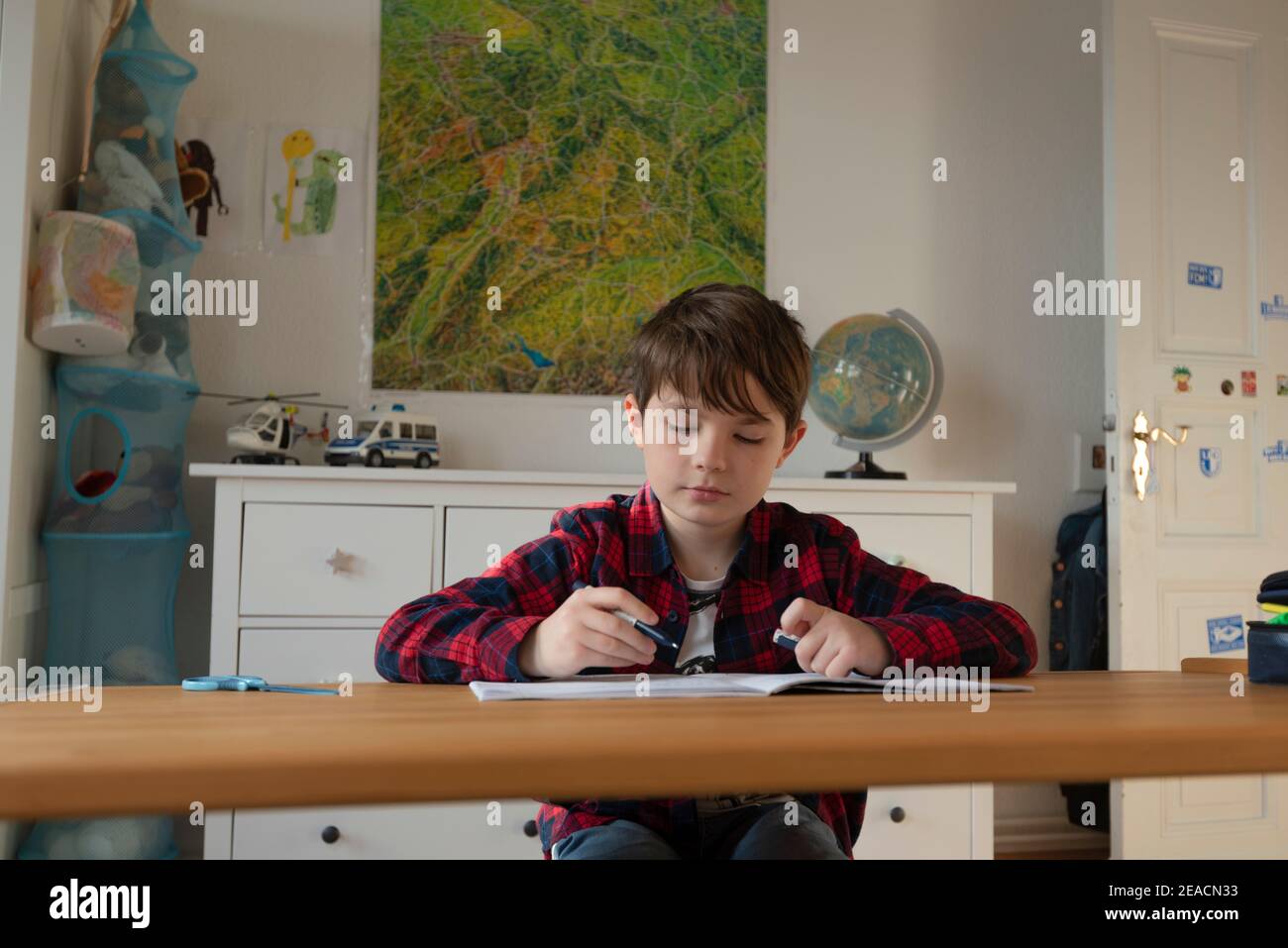 A boy sits at his desk in homeschooling doing chores for school Stock ...