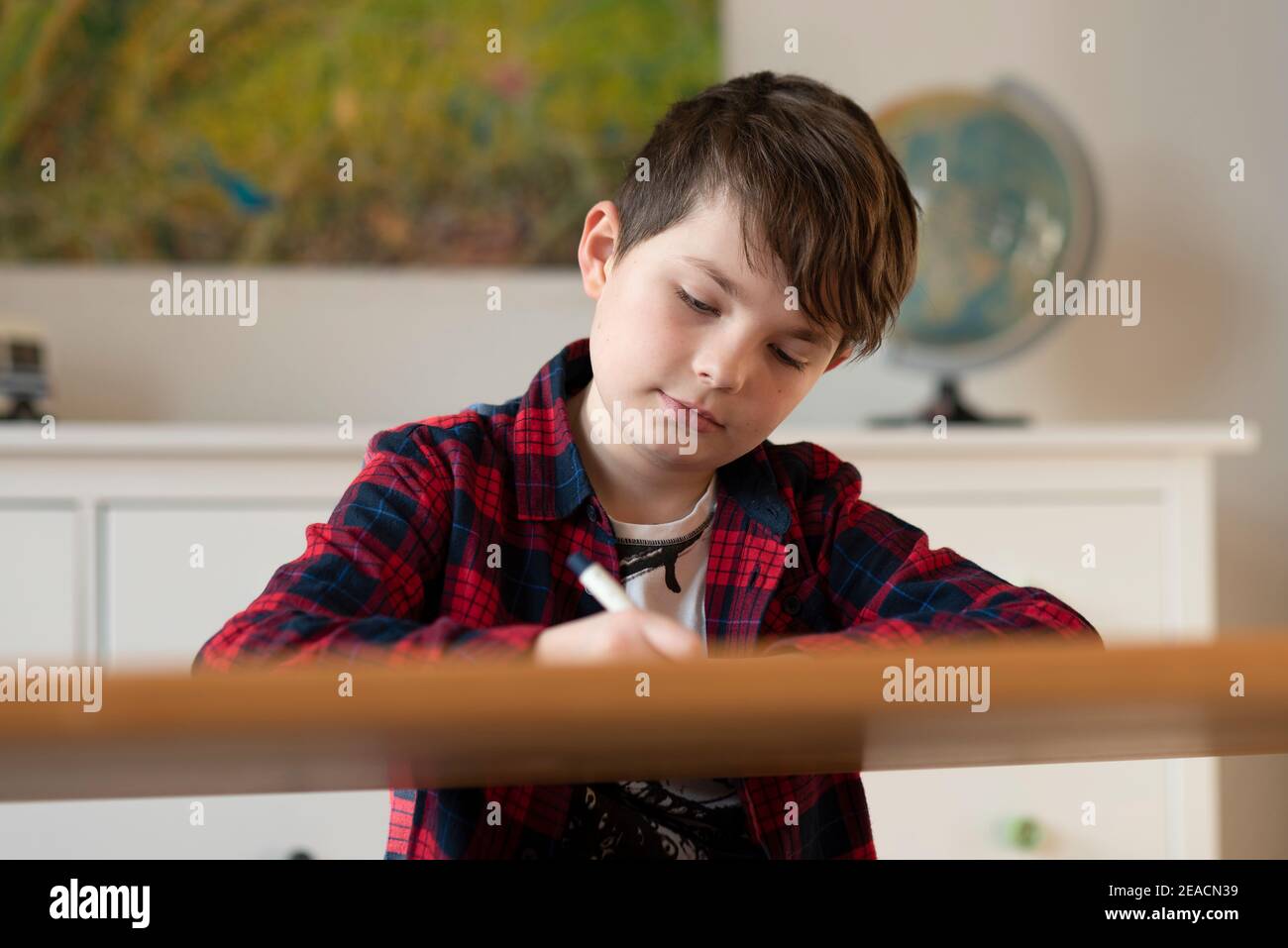 A boy sits at his desk in homeschooling doing chores for school Stock ...