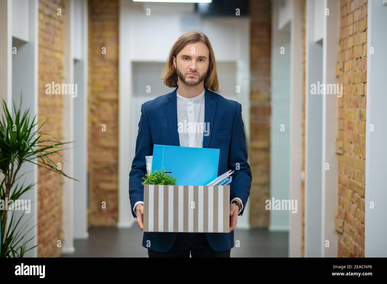Sad young adult man carrying a box Stock Photo - Alamy