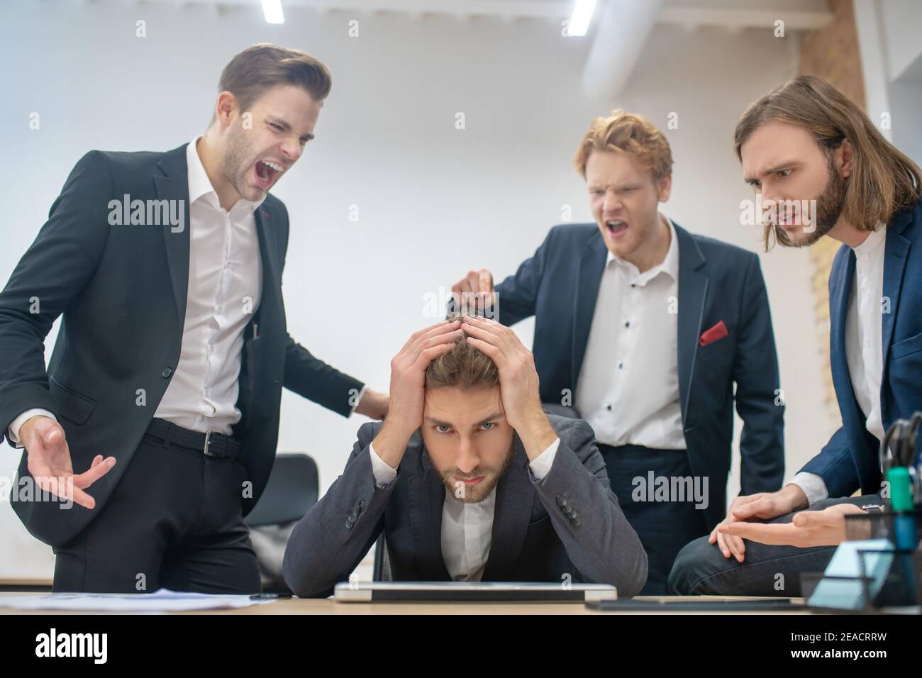 Man at table and his colleagues accusing him Stock Photo - Alamy