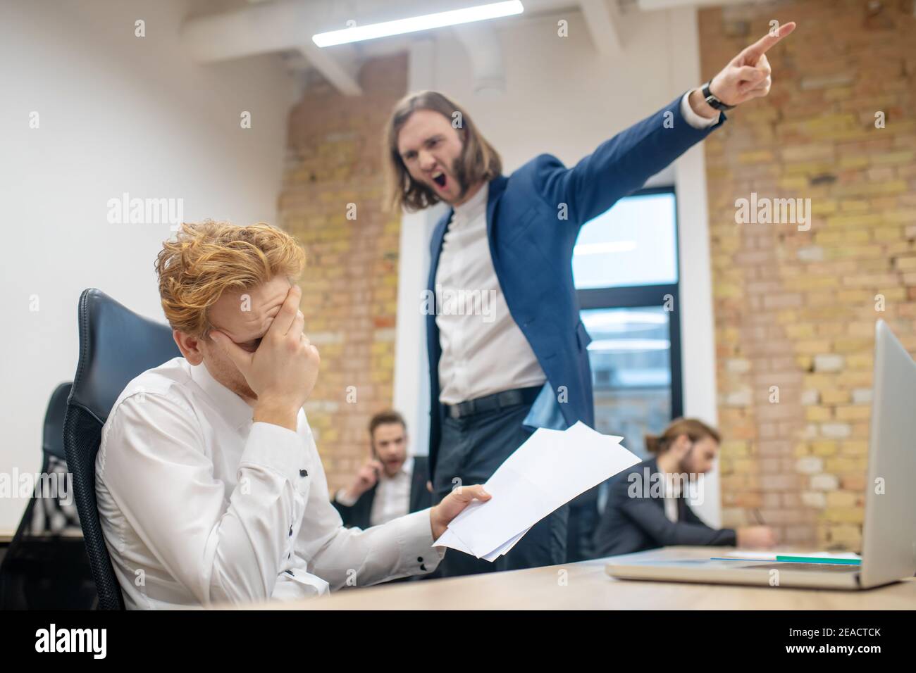 Unhappy man with papers and angry colleague Stock Photo - Alamy