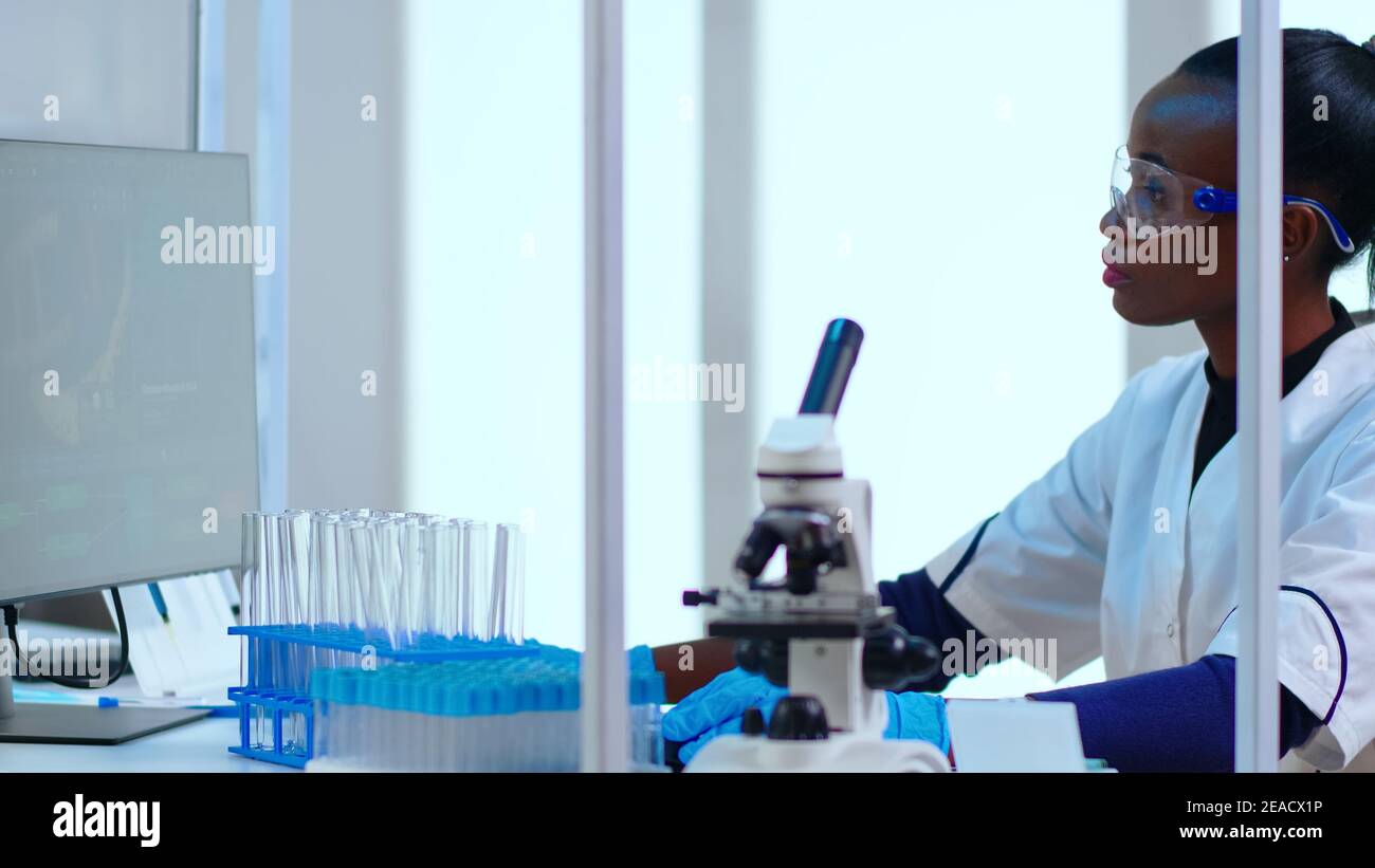 Black woman chemist typing on pc checking virus development in modern ...