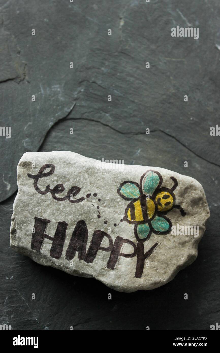painted stone "bee happy Stock Photo - Alamy