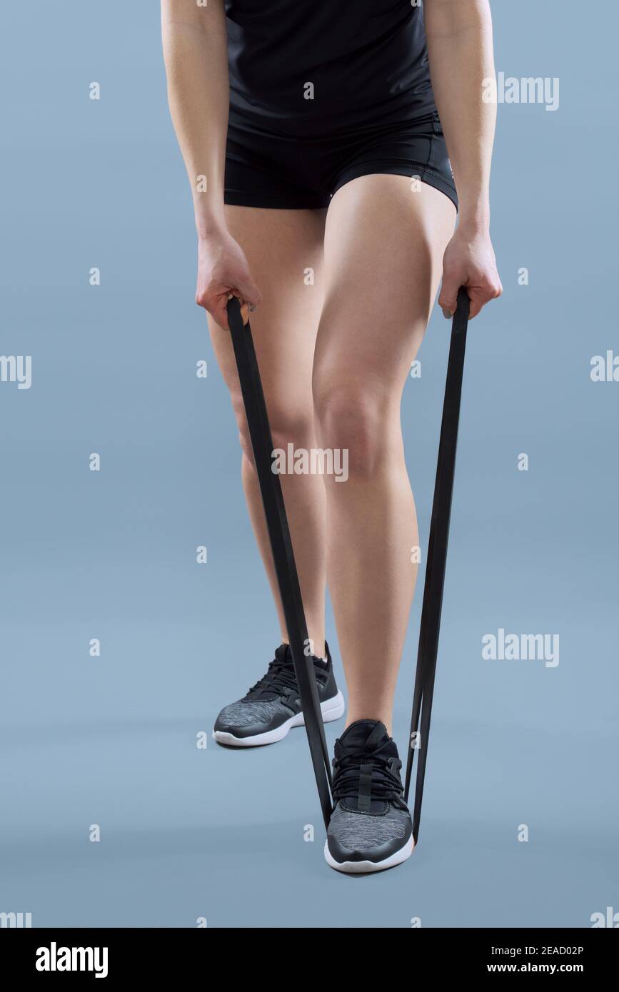 Close up legs of athletic woman doing exercises using fitness elastic ...
