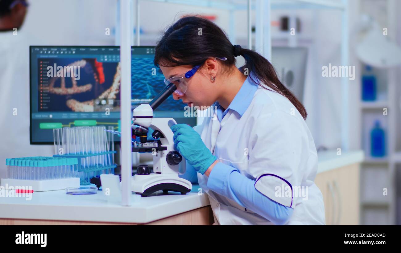 Scientist woman with microscope examining samples and liquid working in ...