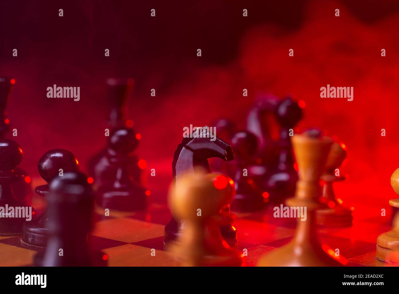 Chess fight, chess pieces on the board, toned in red. Battle fire and ...